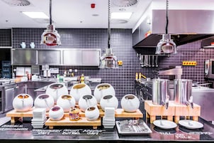 Uma cozinha moderna com várias estações de serviço, incluindo recipientes com comida e utensílios.
