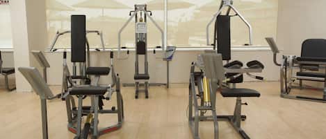 Uma academia com diversos equipamentos de exercício, incluindo um aparelho de leg press, chest press e supino.