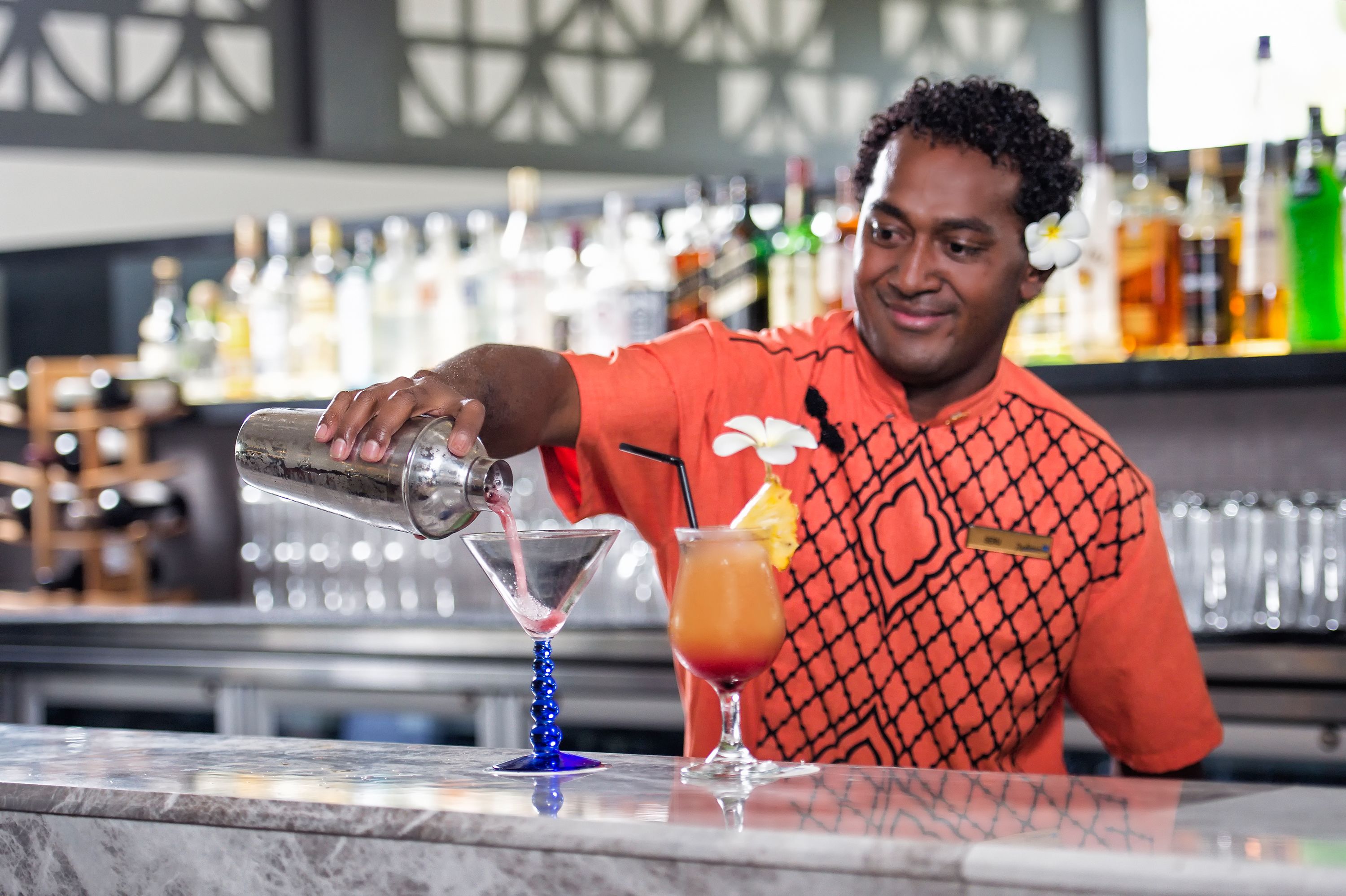 Um bartender servindo uma bebida num copo de martini.