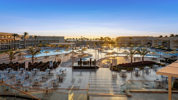 Área de piscina de resort com várias piscinas, espreguiçadeiras e mobiliário de exterior.