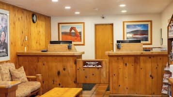 Uma área de recepção com painéis de madeira, um sofá, um banco e um aviso para registrar animais de estimação no momento do check-in.
