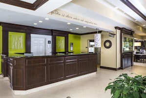 Bancada de recepção com placa indicando 'jardim é onde a natureza e a imaginação se encontram'.