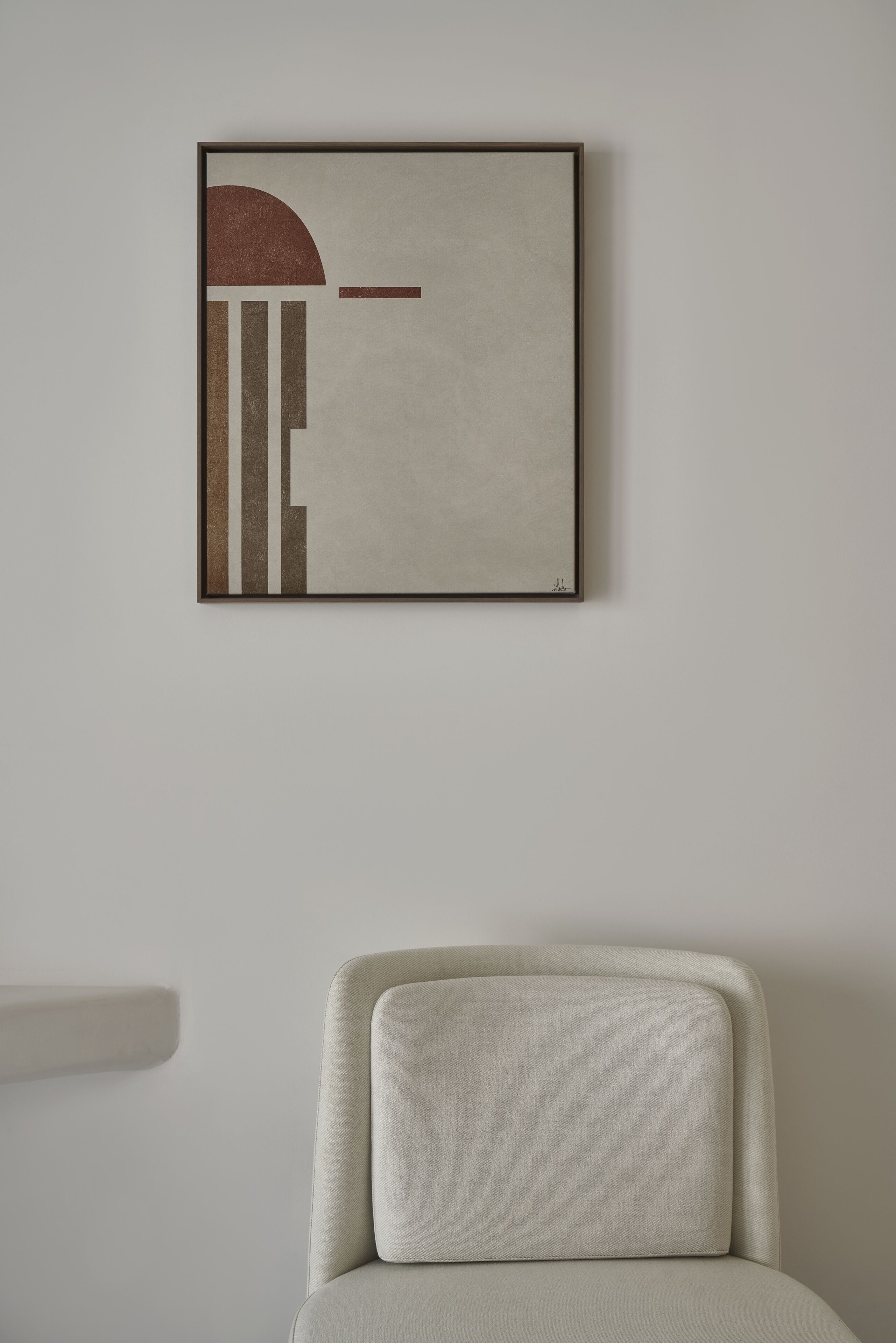 Obra de arte abstrata emoldurada numa parede acima de um sofá.