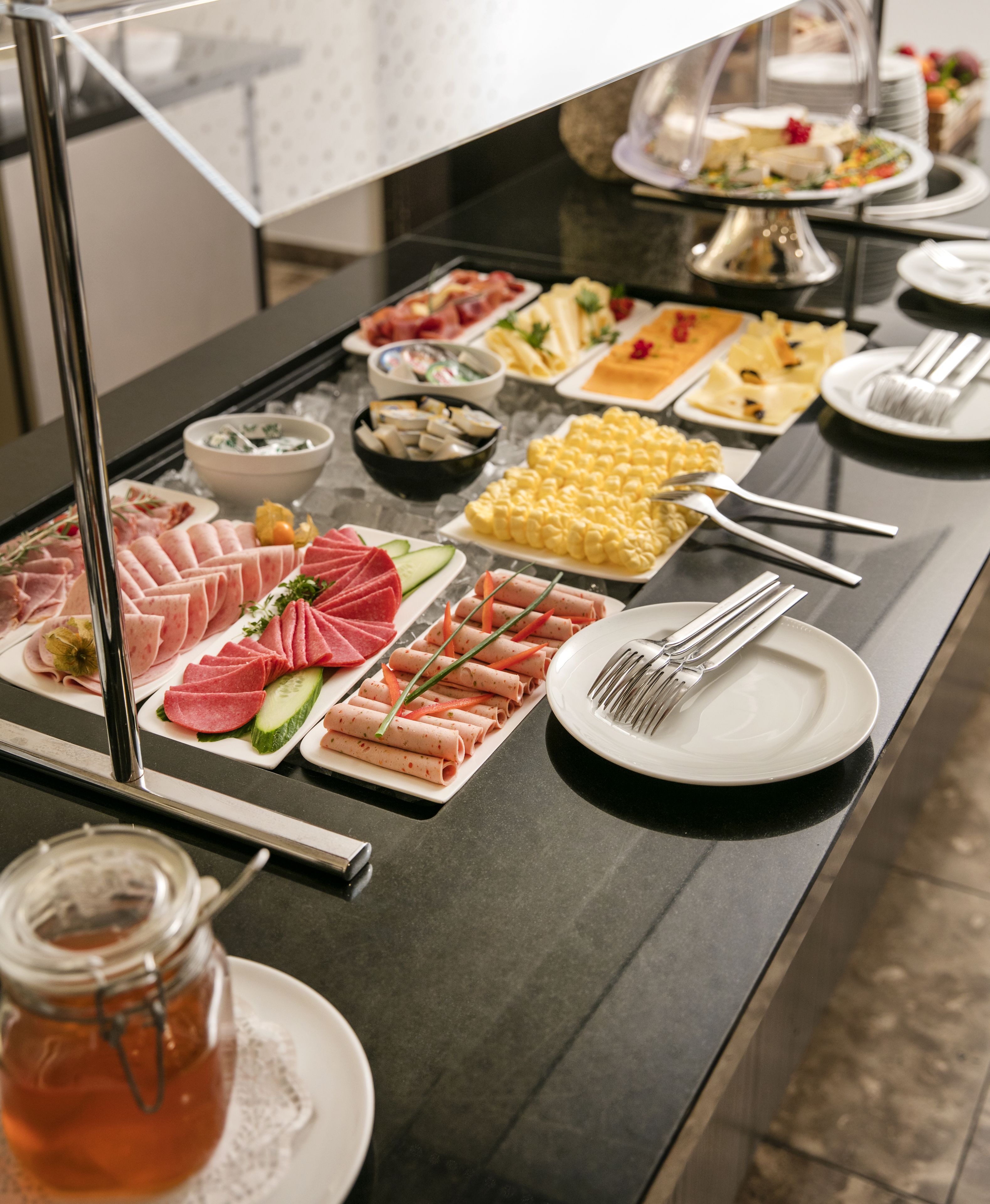 Um buffet com diversos alimentos, incluindo carnes, queijos e legumes.