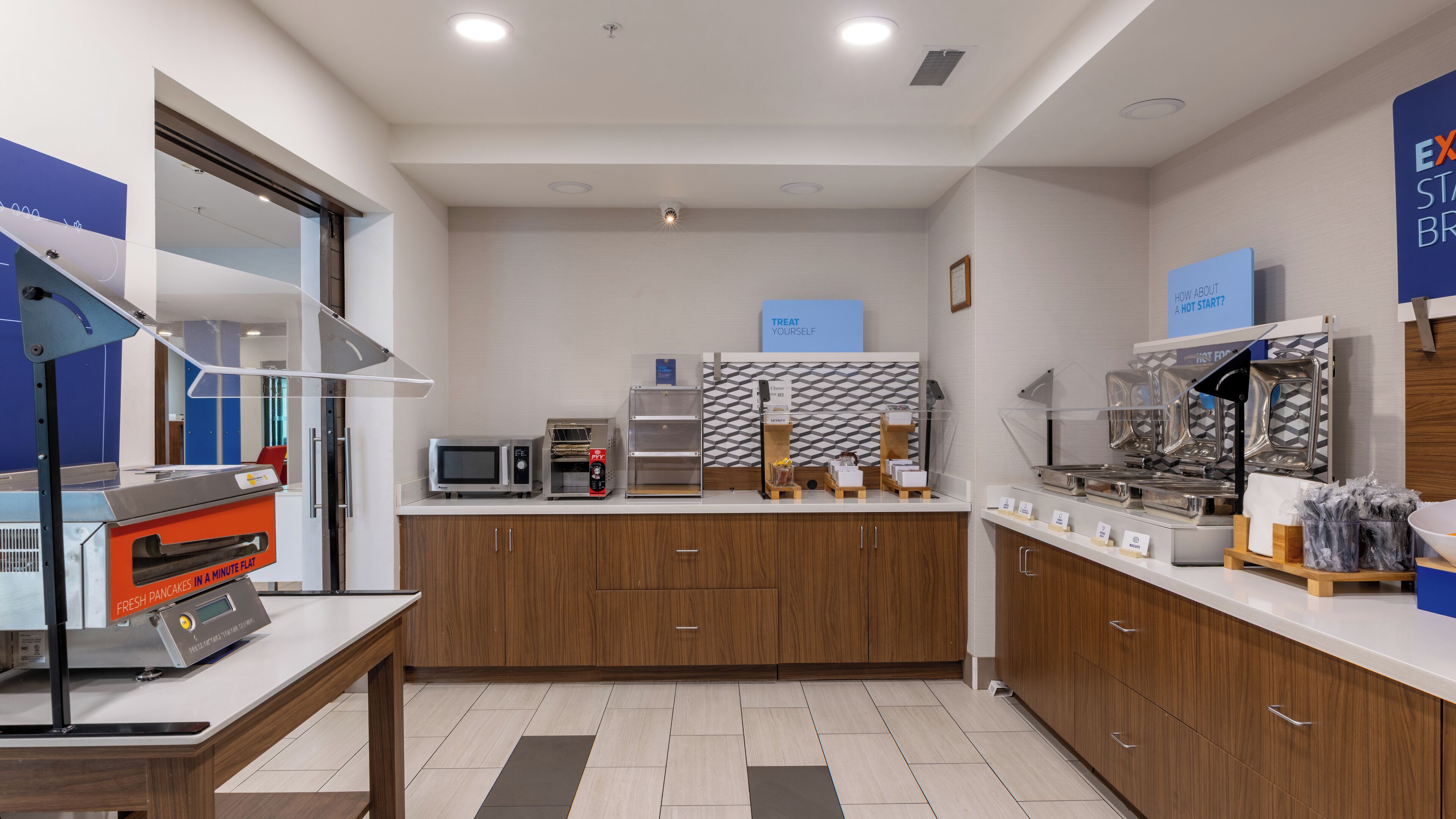 Cozinha moderna com micro-ondas, torradeira e máquina de café. Armários de madeira e bancada com diversos objetos.