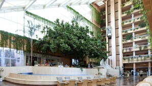 Um átrio amplo com área de estar central, escadaria e várias varandas com vegetação.