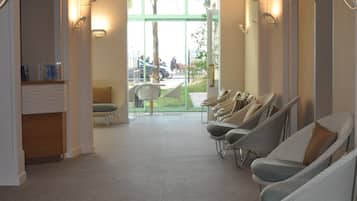 Uma área de espera com balcão de recepção, mesa de atendimento e espaço para sentar com cadeiras.