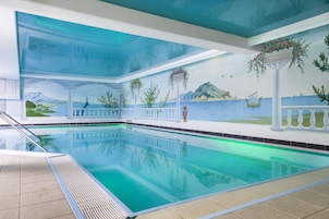 Piscina interior com um mural de uma paisagem costeira, incluindo montanhas, um navio e um pavão.