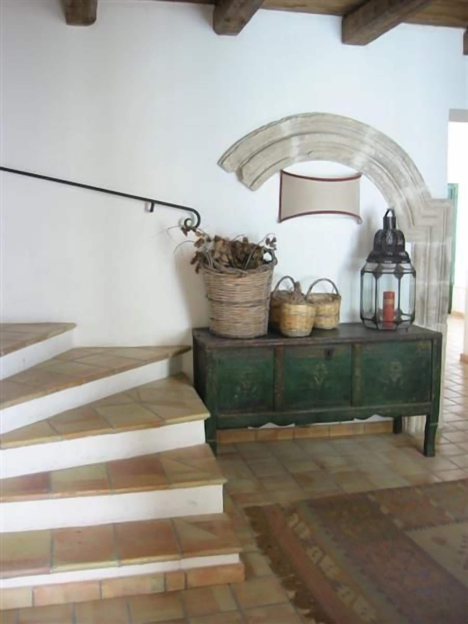 Uma escadaria com um console verde ao lado, decorado com cestos e um candeeiro.