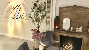 Um quarto com lareira, uma cadeira, um vaso com flores e um painel com um aviso.