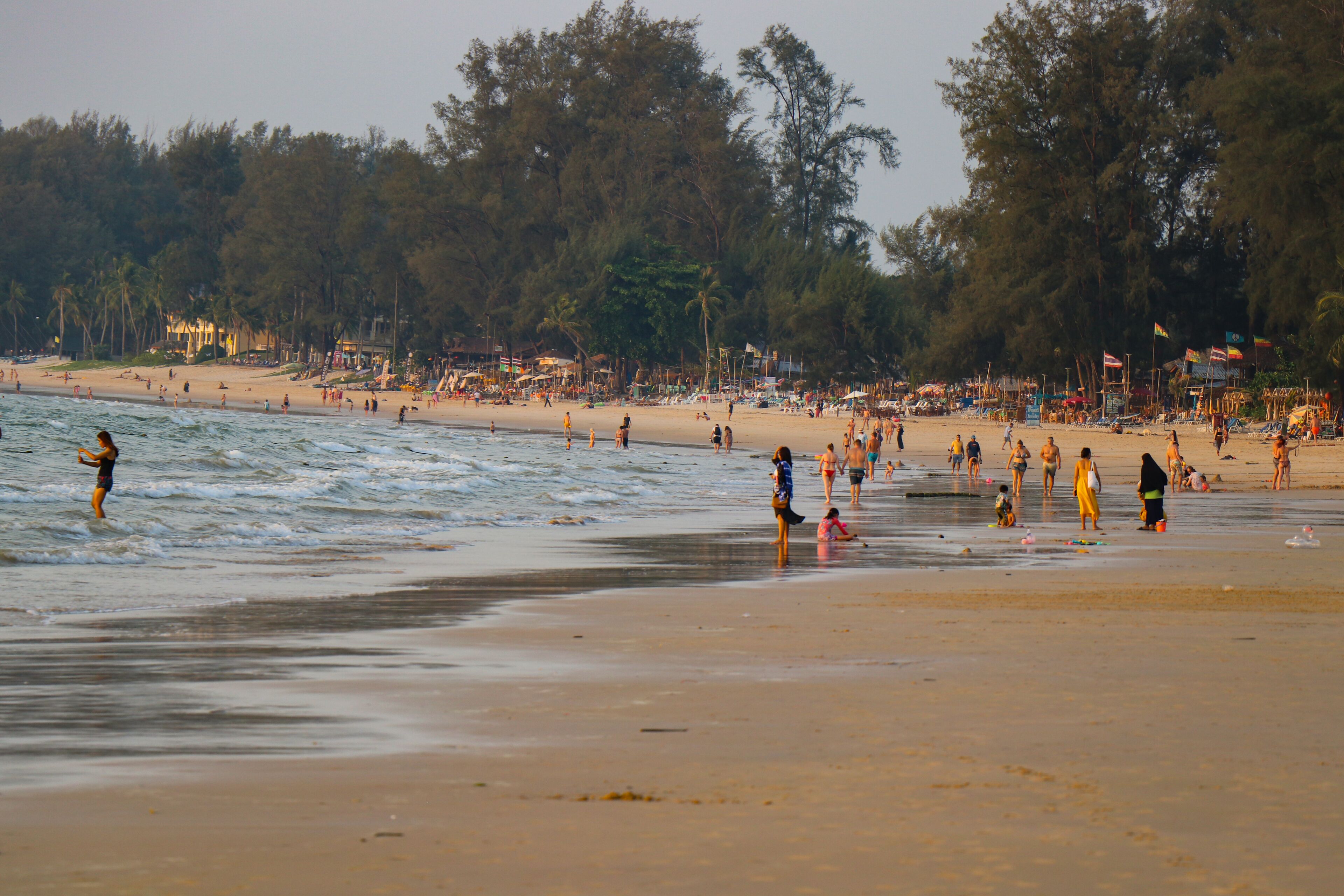 Uma praia com pessoas nadando e caminhando pela orla.