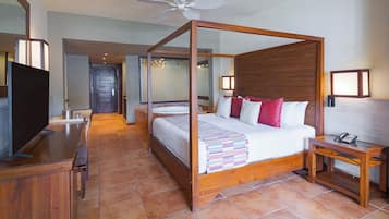 Um quarto de hotel espaçoso com cama de dossel, escrivaninha de madeira, televisão e mesa de cabeceira separada.