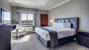 Quarto de hotel com uma cama grande, uma escrivaninha, uma cadeira e janela com vista.
