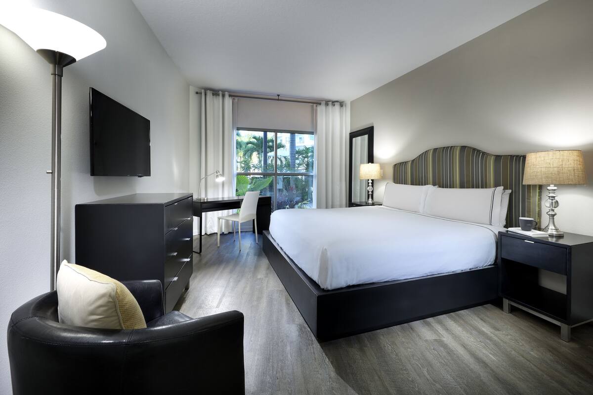 Quarto de hotel moderno com uma cama grande, uma mesa e uma cadeira.