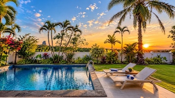 Piscina com espreguiçadeiras e palmeiras, rodeada por um jardim bem cuidado.