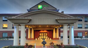 Edifício da Holiday Inn Express & Suites com entrada central, colunas e uma fonte.