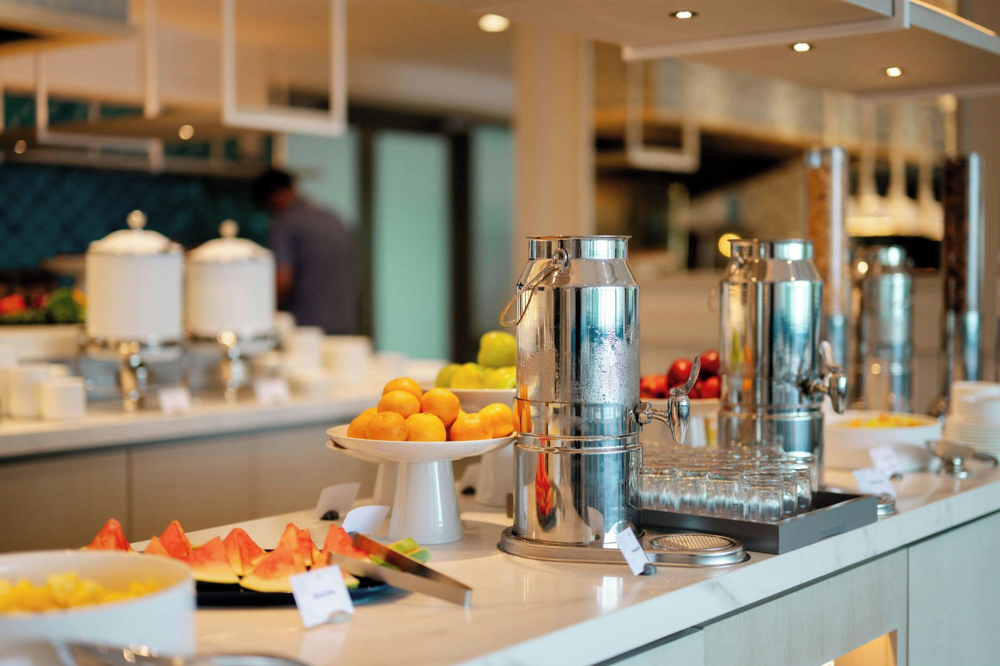 Disposição de buffet com diversos alimentos e dispensadores de bebidas.
