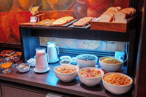Buffet de café da manhã com diversas opções de comida e um espaço para café.