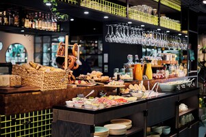 Uma área de buffet com diversos alimentos, utensílios e copos.