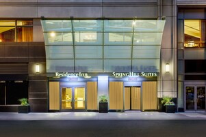 Um hotel com fachada moderna, apresentando duas entradas principais identificadas como "Residence Inn" e "Springhill Suites".