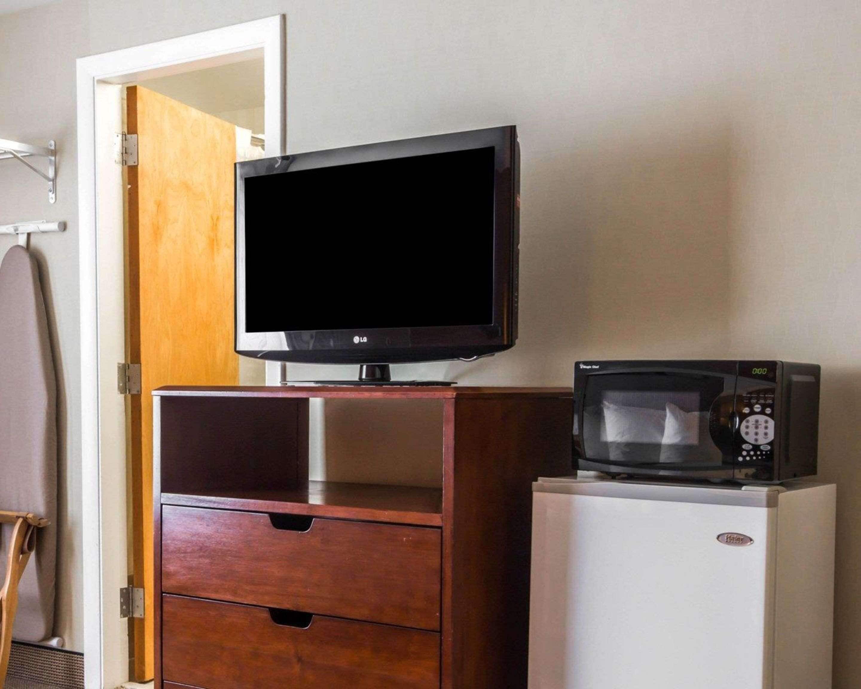Quarto com um armário de madeira, televisão e micro-ondas.