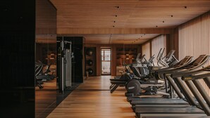 Uma academia com esteiras, bicicletas ergométricas e aparelhos de musculação.