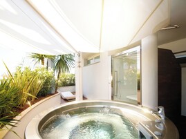 Área de spa moderna com hidromassagem, box de vidro para chuveiro e espaço de estar com vista para o exterior.