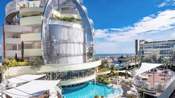 Um hotel moderno com arquitetura curva única, área de piscina e assentos ao ar livre.