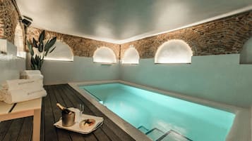 Uma área de spa com piscina, deck de madeira e parede de tijolos.
