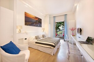 Quarto de hotel moderno com uma cama, uma escrivaninha com um laptop, uma cadeira e um quadro na parede.