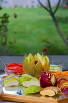 Uma tábua de madeira com uma seleção de frutas, incluindo maçãs, peras e melão fatiados.