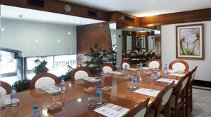 Uma sala de conferências com uma mesa comprida, cadeiras, garrafas de água e documentos.
