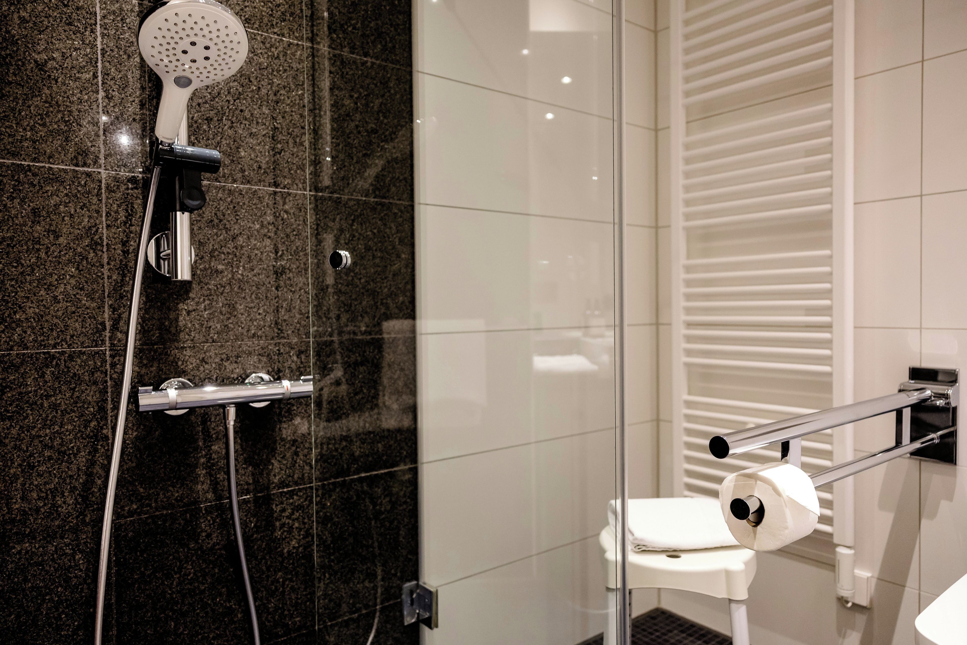 Uma casa de banho moderna com chuveiro, sanita e porta-toalhas.