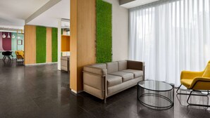 Um hall moderno com um sofá de couro, uma poltrona amarela e uma mesa de centro de vidro.