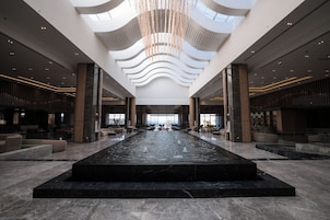 Um hall amplo com um elemento central de água, pé-direito alto e decoração moderna.