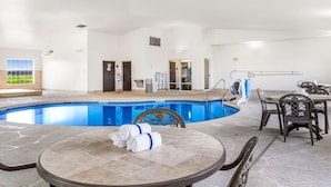 Uma área de piscina com mesa e cadeiras, uma porta e uma janela com vista.