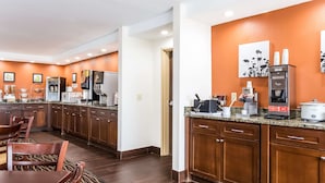 Uma cozinha moderna com armários de madeira, bancadas de granito e diversos eletrodomésticos, incluindo uma cafeteira e uma torradeira.