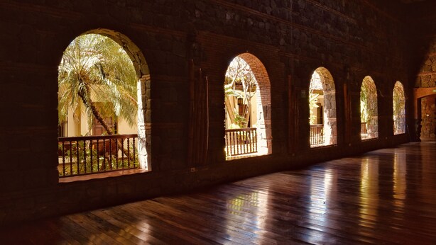Um corredor com janelas em arco e soalho de madeira.