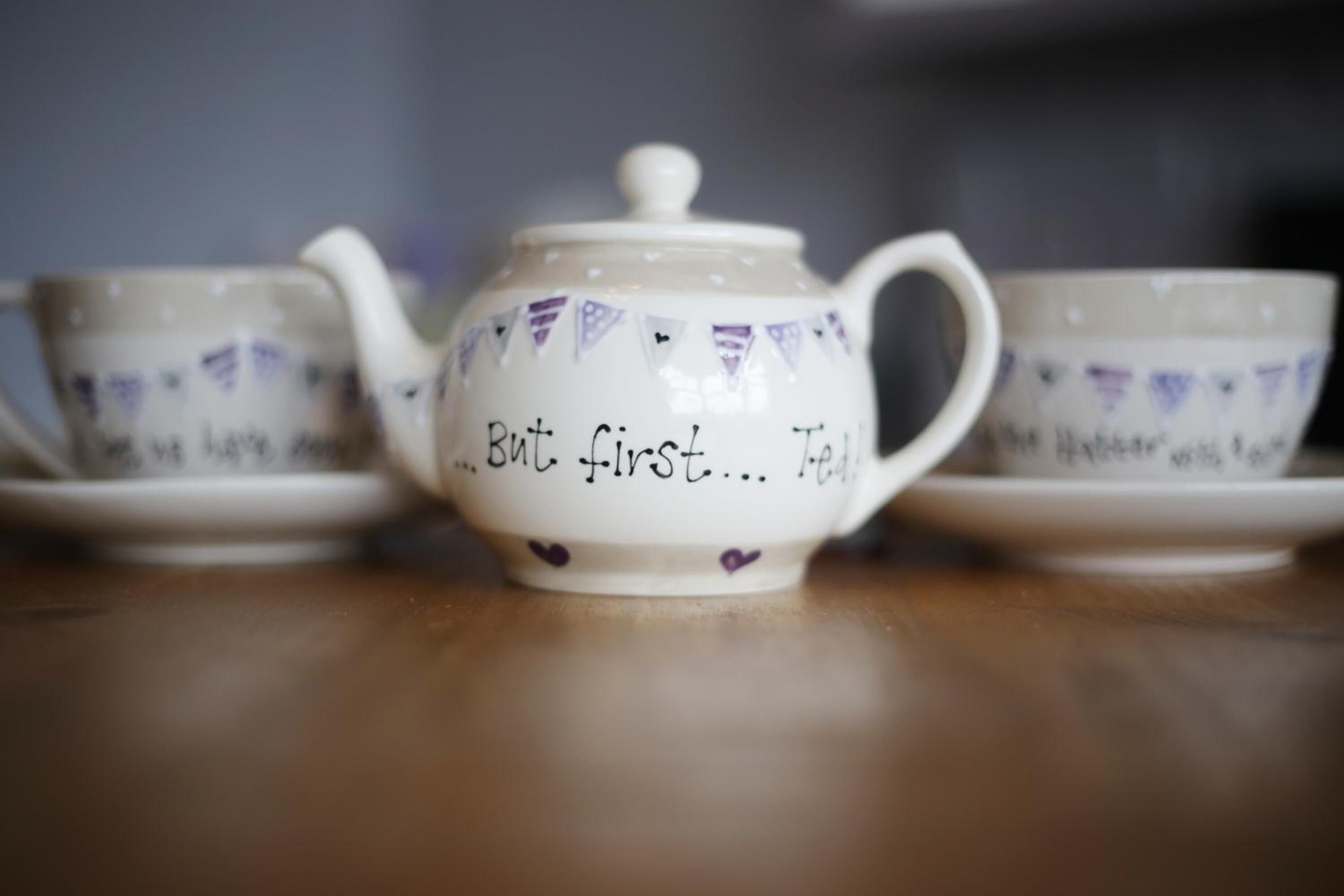 Um bule e três xícaras com padrão decorativo e texto.