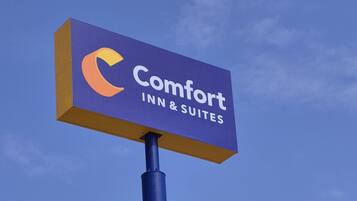 Placa da Comfort Inn & Suites, com um céu azul claro ao fundo.