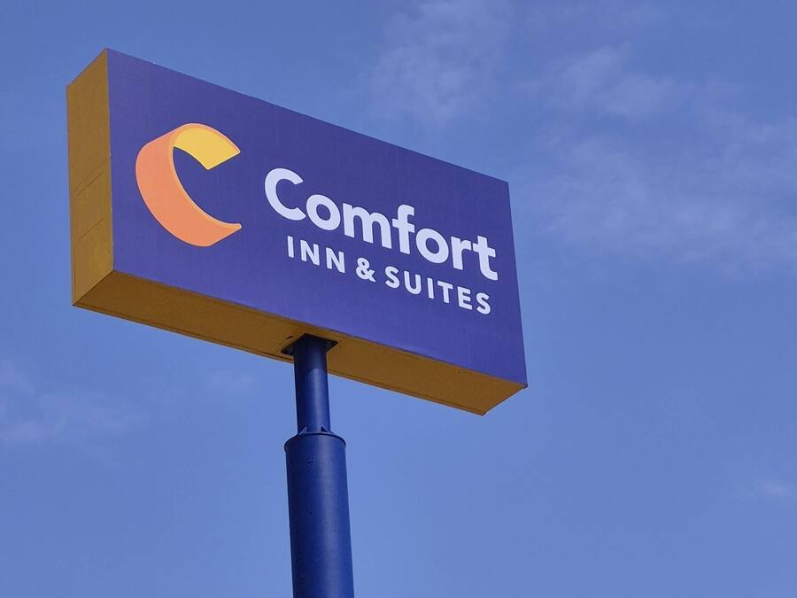 Placa da Comfort Inn & Suites, com um céu azul claro ao fundo.