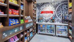 Uma área com petiscos e bebidas, com prateleiras repletas de salgadinhos, refrigerantes e outros produtos.