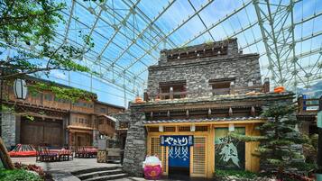 Um edifício japonês tradicional com fachada de pedra, vigas de madeira e uma placa azul com caracteres japoneses.