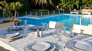 Mesa posta para refeição, com uma piscina ao fundo.