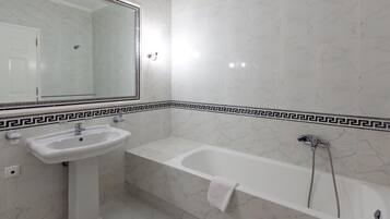 Uma casa de banho com uma pia branca, uma banheira e um espelho grande.