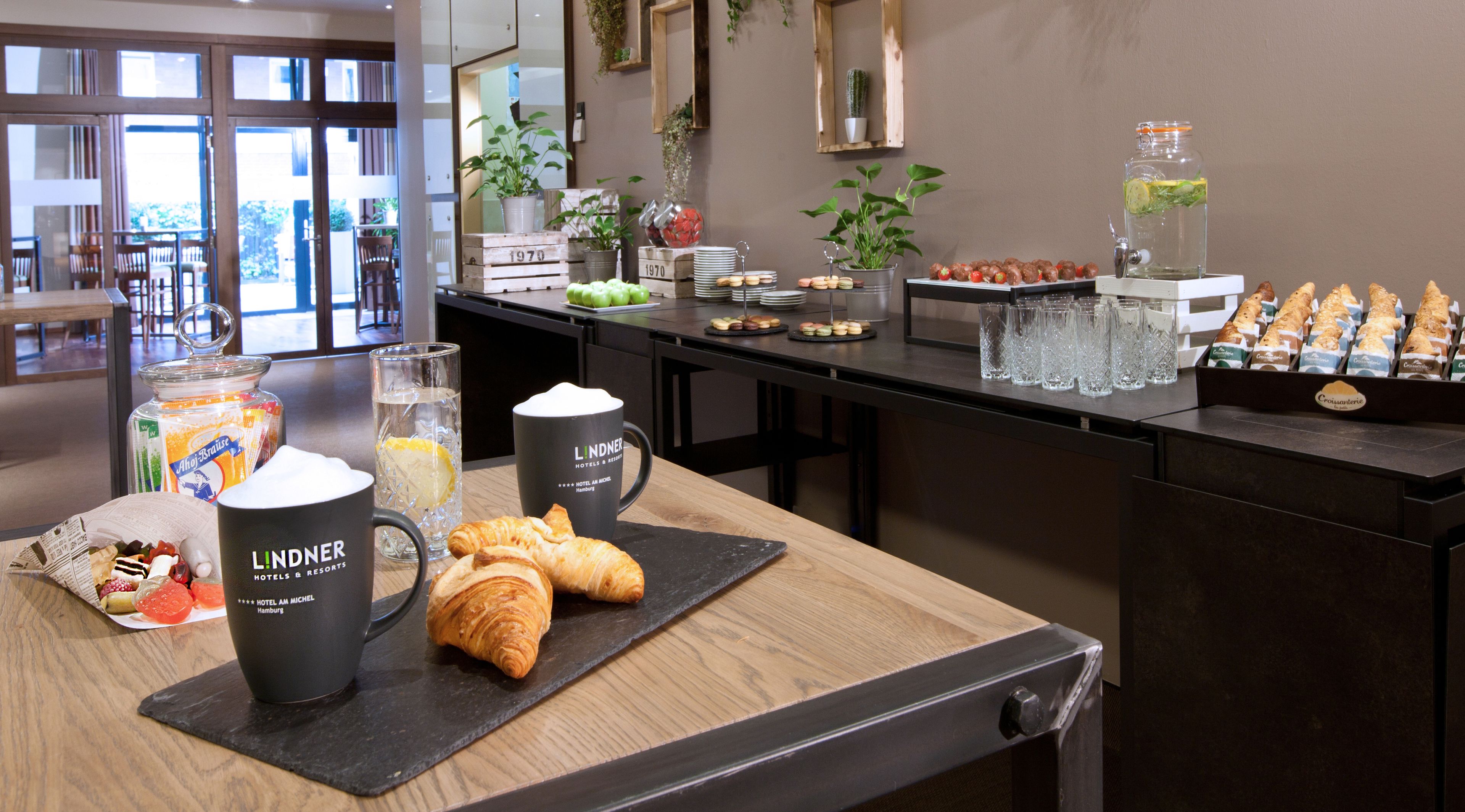 Um buffet de café da manhã com croissants, doces e diversas bebidas.