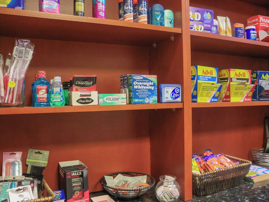 Estante de farmácia repleta de diversos produtos de higiene bucal, incluindo creme dental, enxaguante bucal e fio dental.