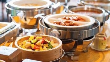 Buffet com diversos alimentos em tigelas de metal e madeira.