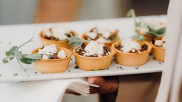 Uma bandeja de mini quiches com um enfeite, sendo segurada por alguém.