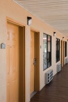 Um corredor com portas, cada uma delas numerada, dando acesso a quartos individuais.